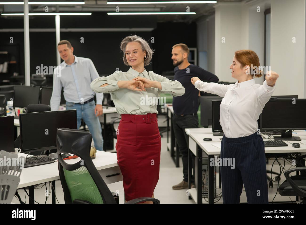 Four office workers warm up during a break. Employees do fitness ...