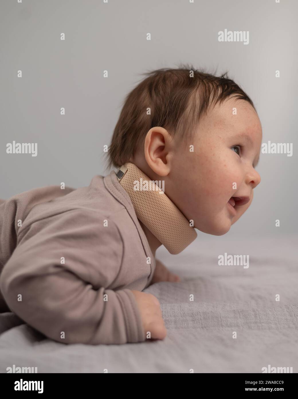 Portrait of a newborn baby lying on his stomach in an orthopedic collar ...