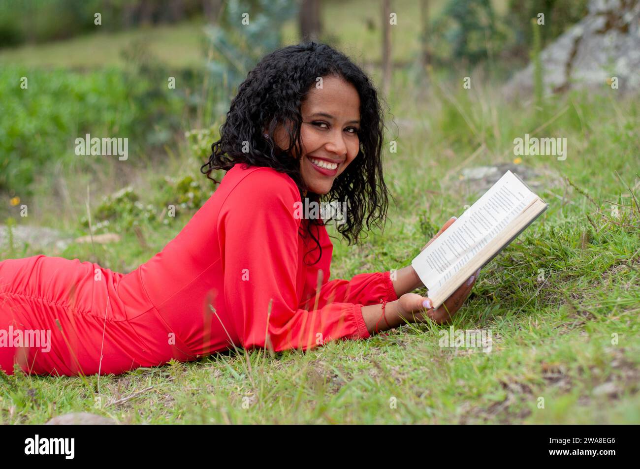 young colombian girl lying face down smiling intensely to the camera ...