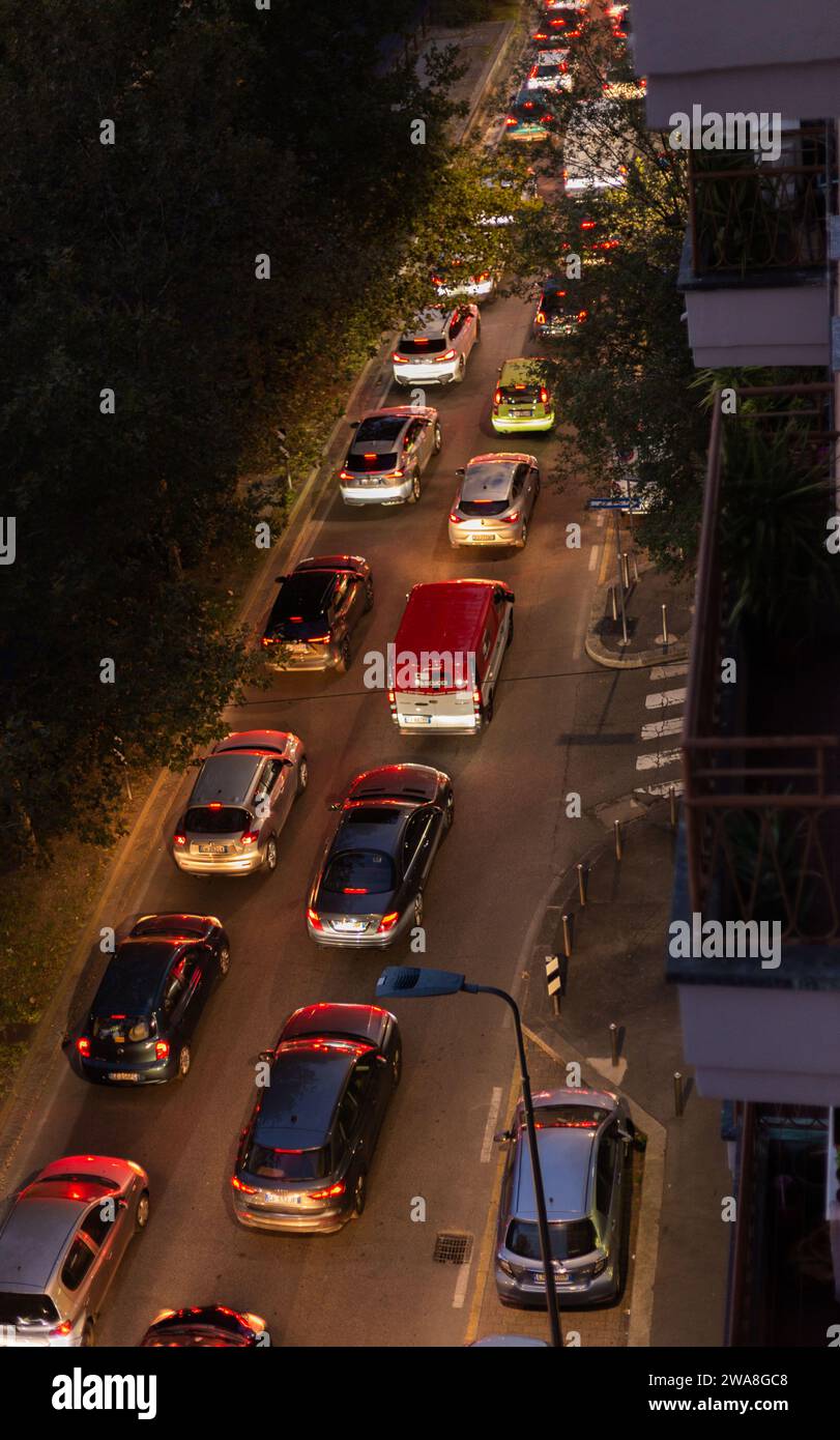 As twilight descends, a line of cars illuminates the evening road ...