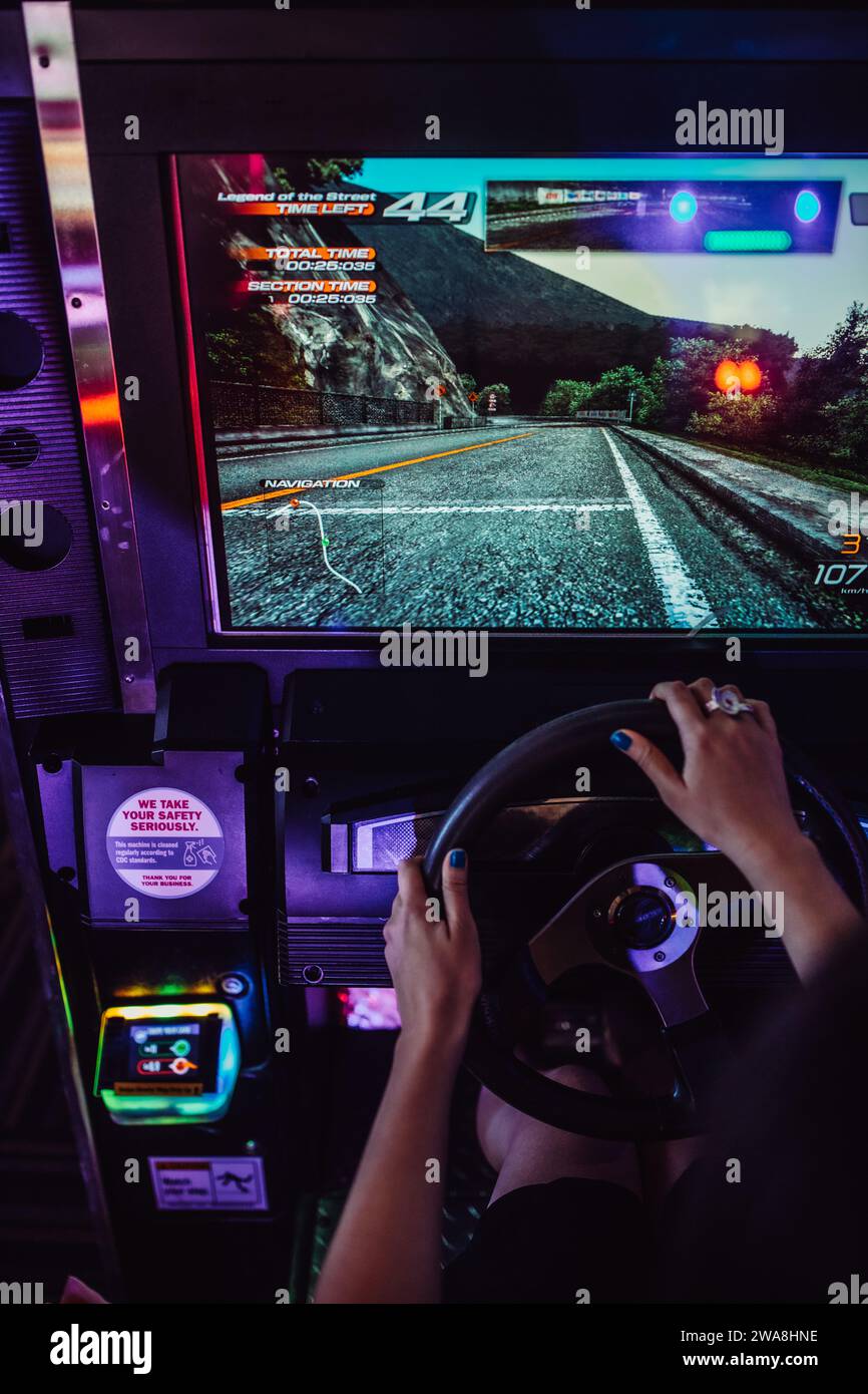 Playing driving game at arcade Stock Photo - Alamy