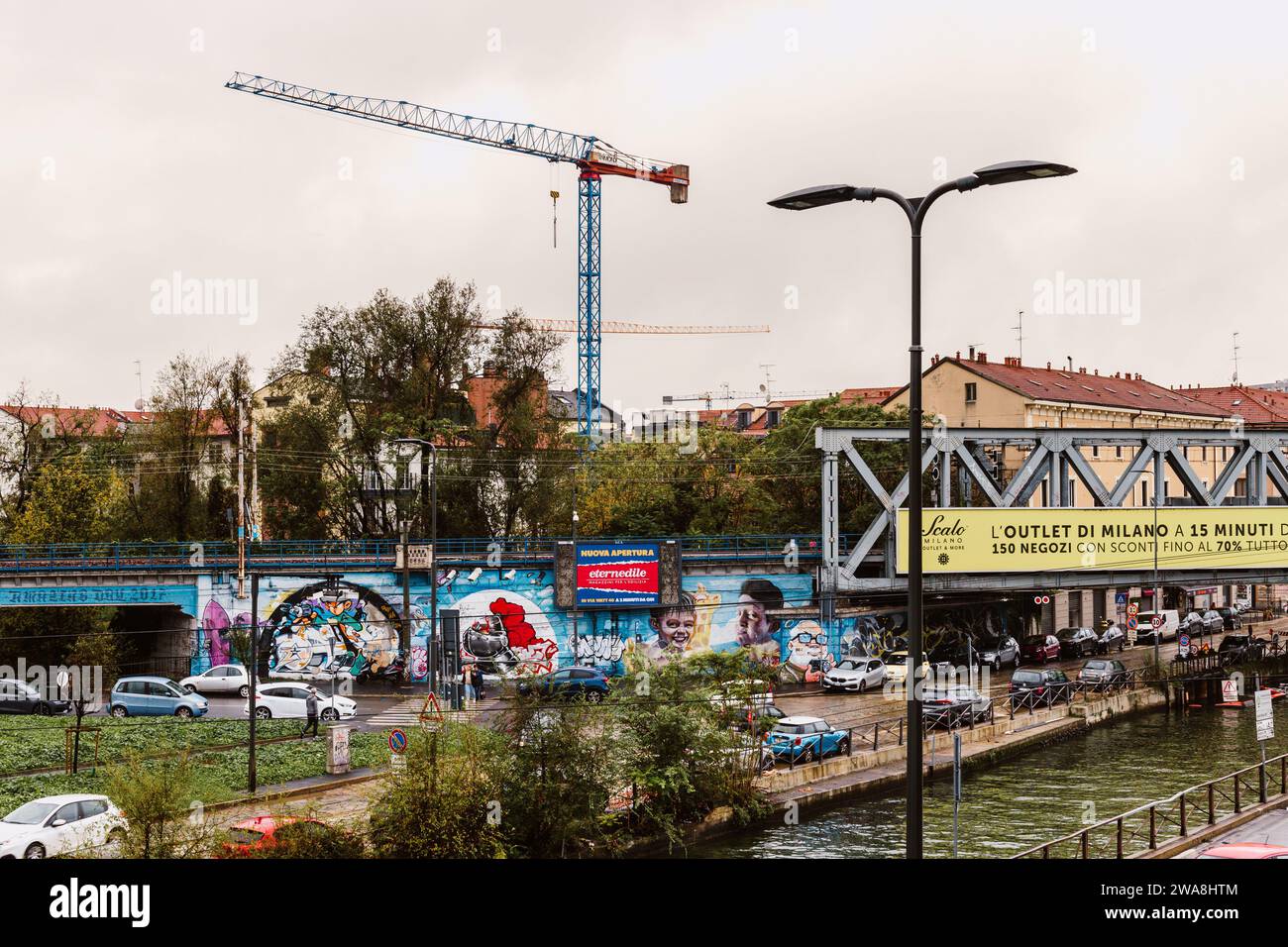 A towering construction crane looms against vibrant city murals ...