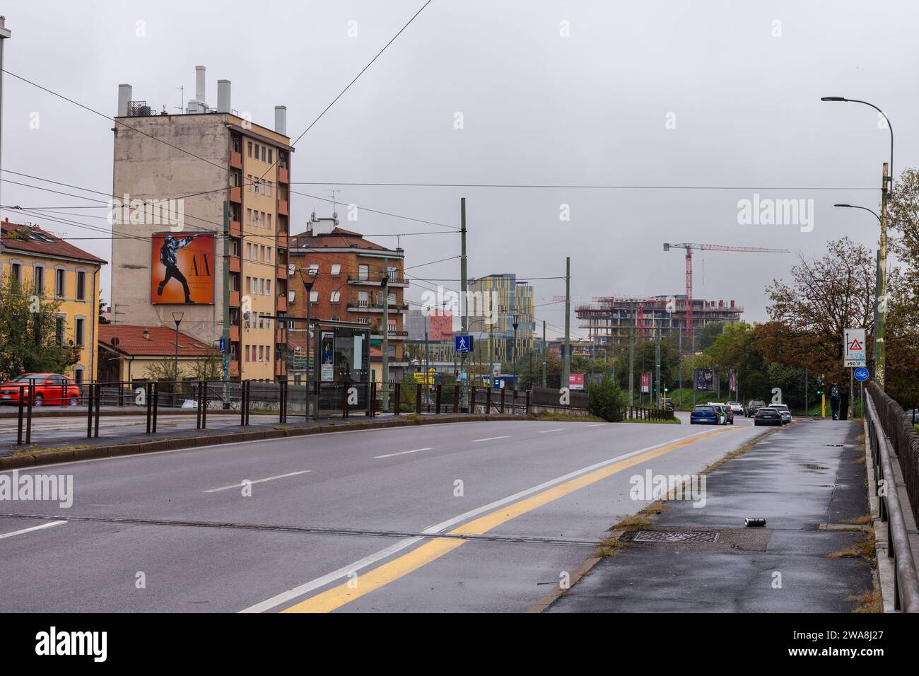 An ordinary grey city road stretches ahead, lined by unassuming ...