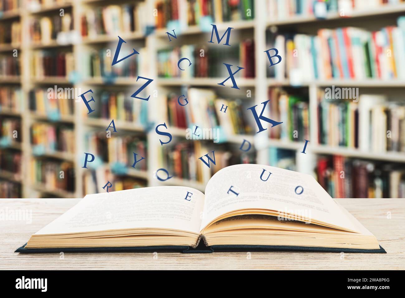 Open book with letters flying out of it in library Stock Photo - Alamy