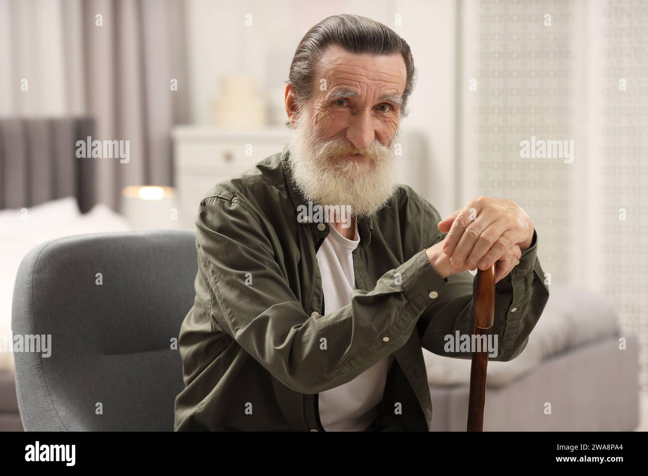 Senior man with walking cane on chair at home Stock Photo - Alamy