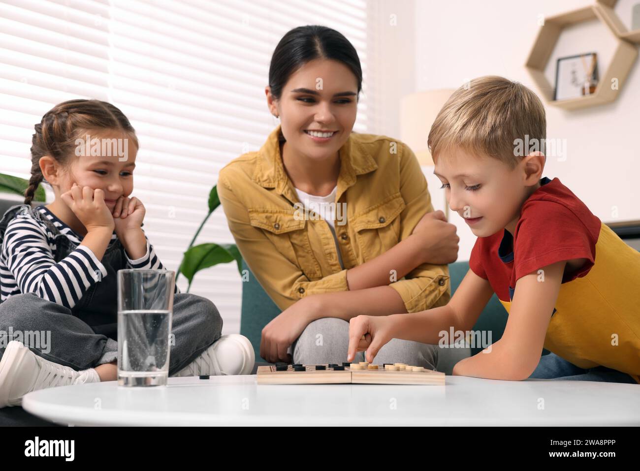 Family playing checkers at coffee table in room Stock Photo - Alamy