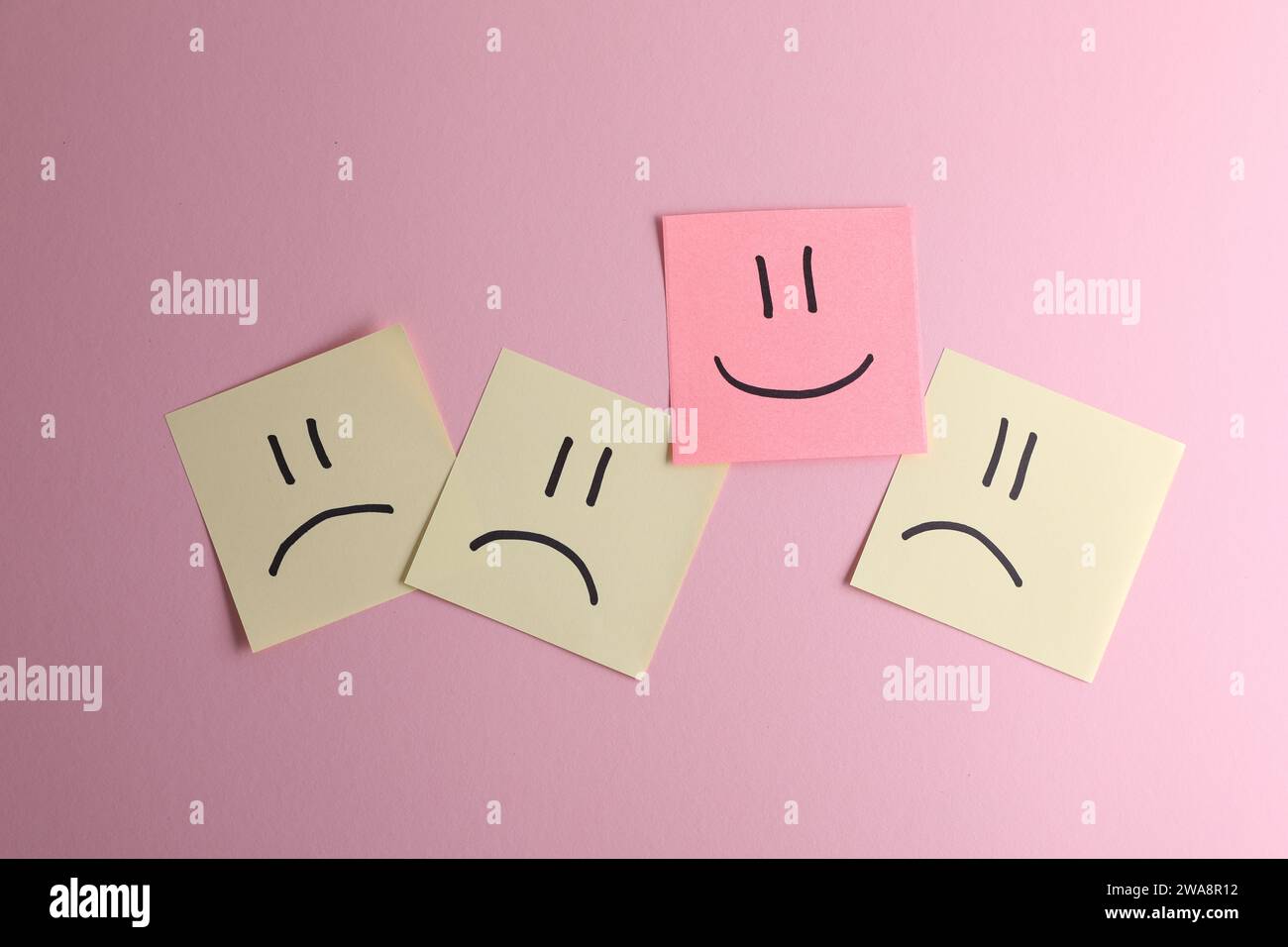 Choice concept. Sticky note with happy emoticon among beige papers with ...
