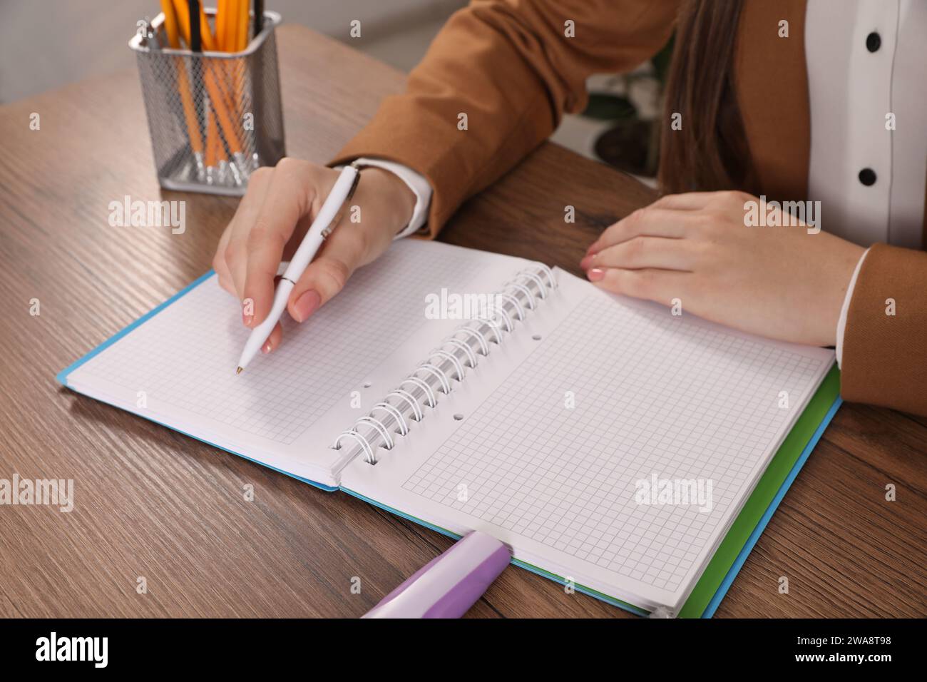 Woman taking notes at wooden table indoors, closeup Stock Photo - Alamy