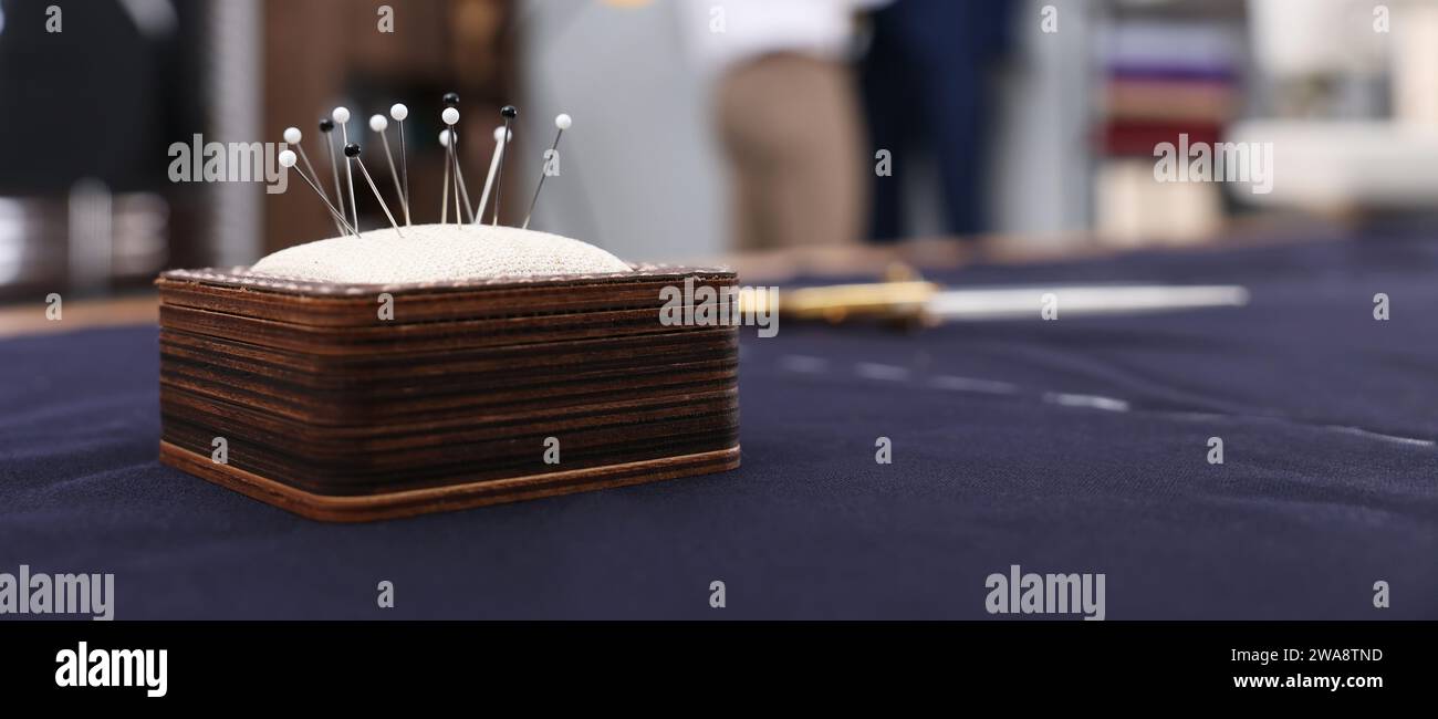 Pin cushion and purple fabric on table in dressmaking workshop, closeup ...