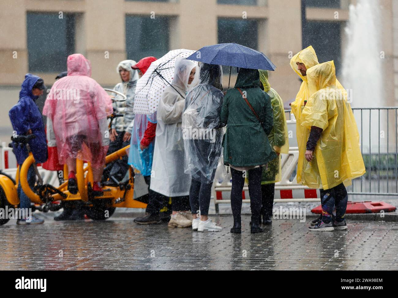 Tourists protect themselves from heavy rainfall with rain capes and ...