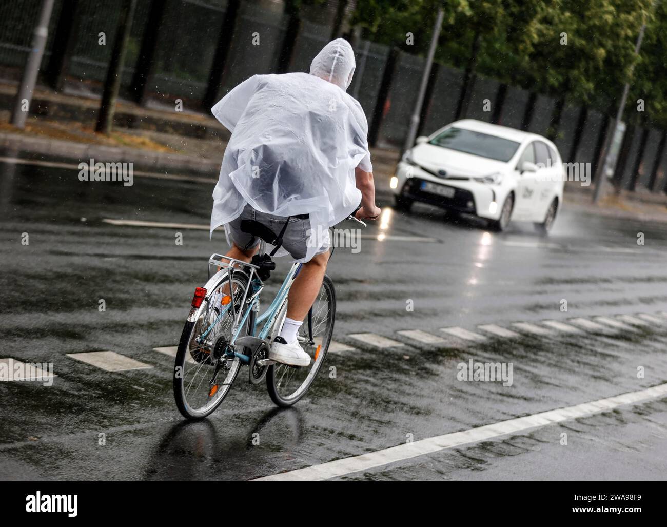 Bicycle rider with rain cape in heavy rain, Berlin, 23.06.2023 Stock ...