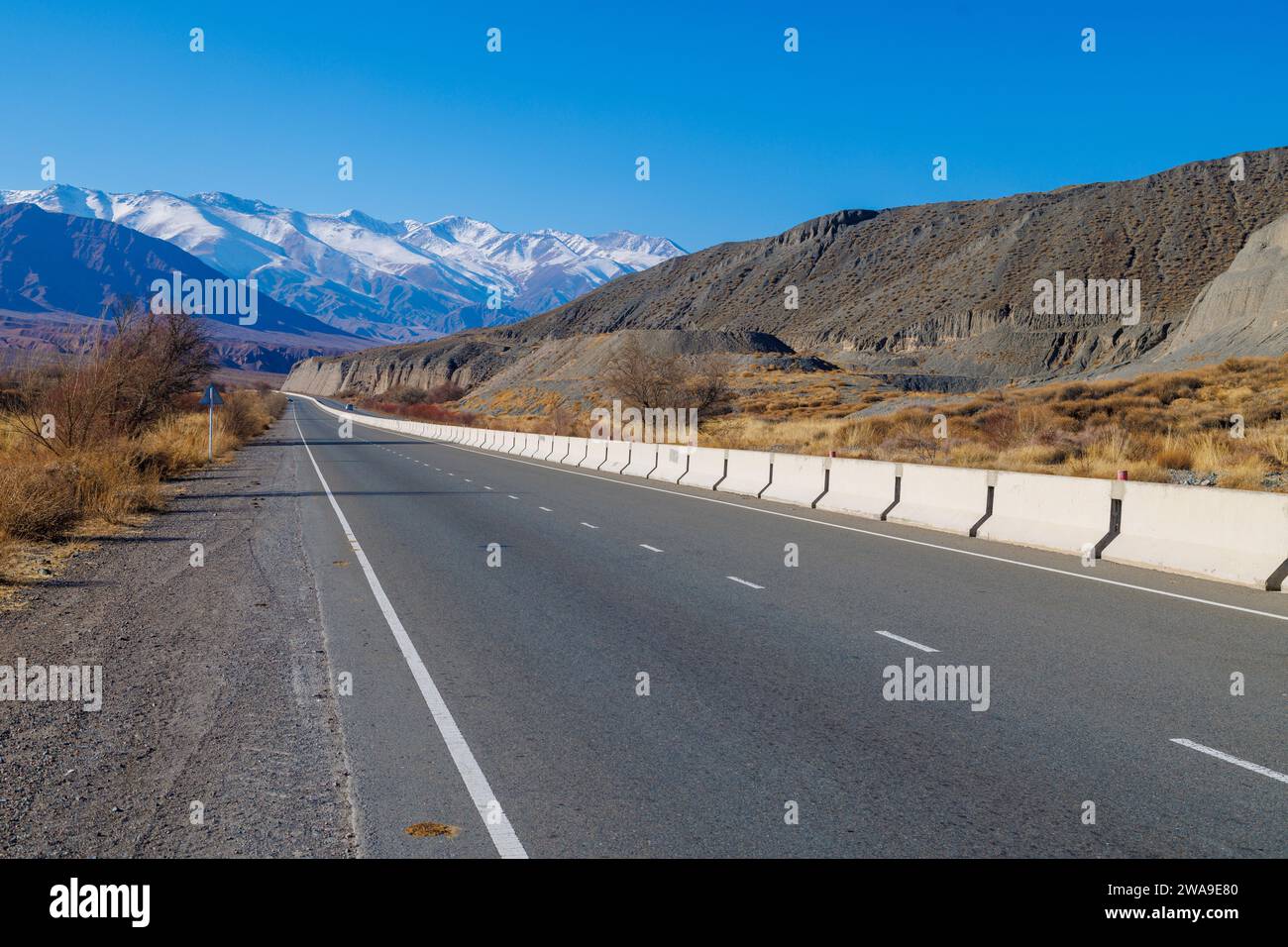 empty highway road with separating concrete barrier in mountains at ...