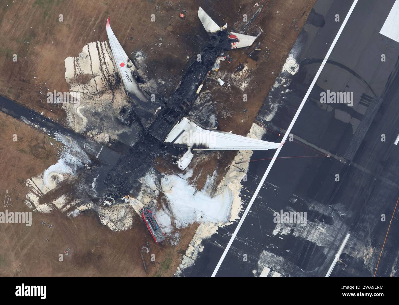 An aerial photo shows Japan Airlines flight 156 burnt on the runway at ...