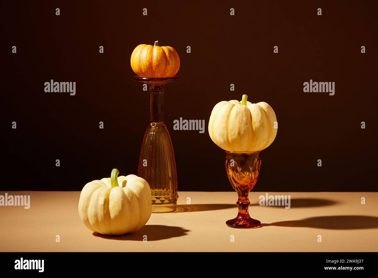Yellow and orange pumpkins decorated on two glasses against dark ...