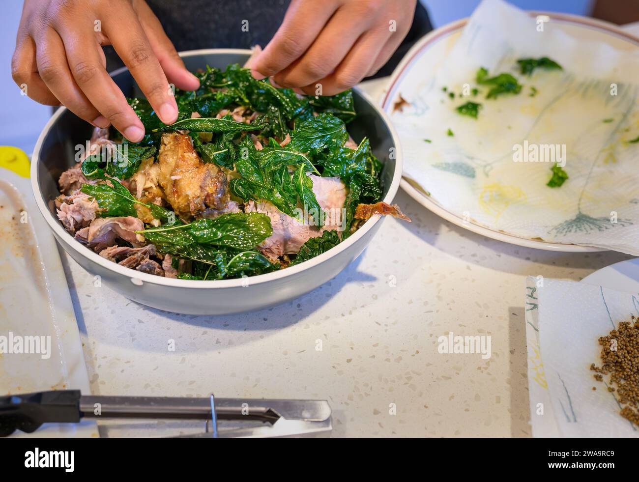 Hands spread fried mint over a leg of roast lamb on the kitchen ...