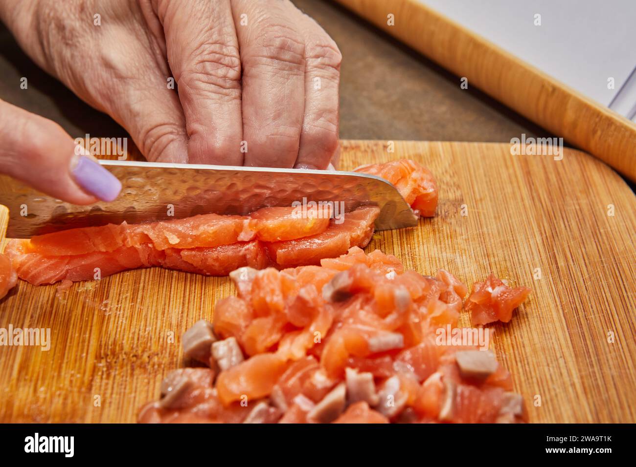 A skilled chefs hands carefully cutting a piece of fresh salmon using a ...