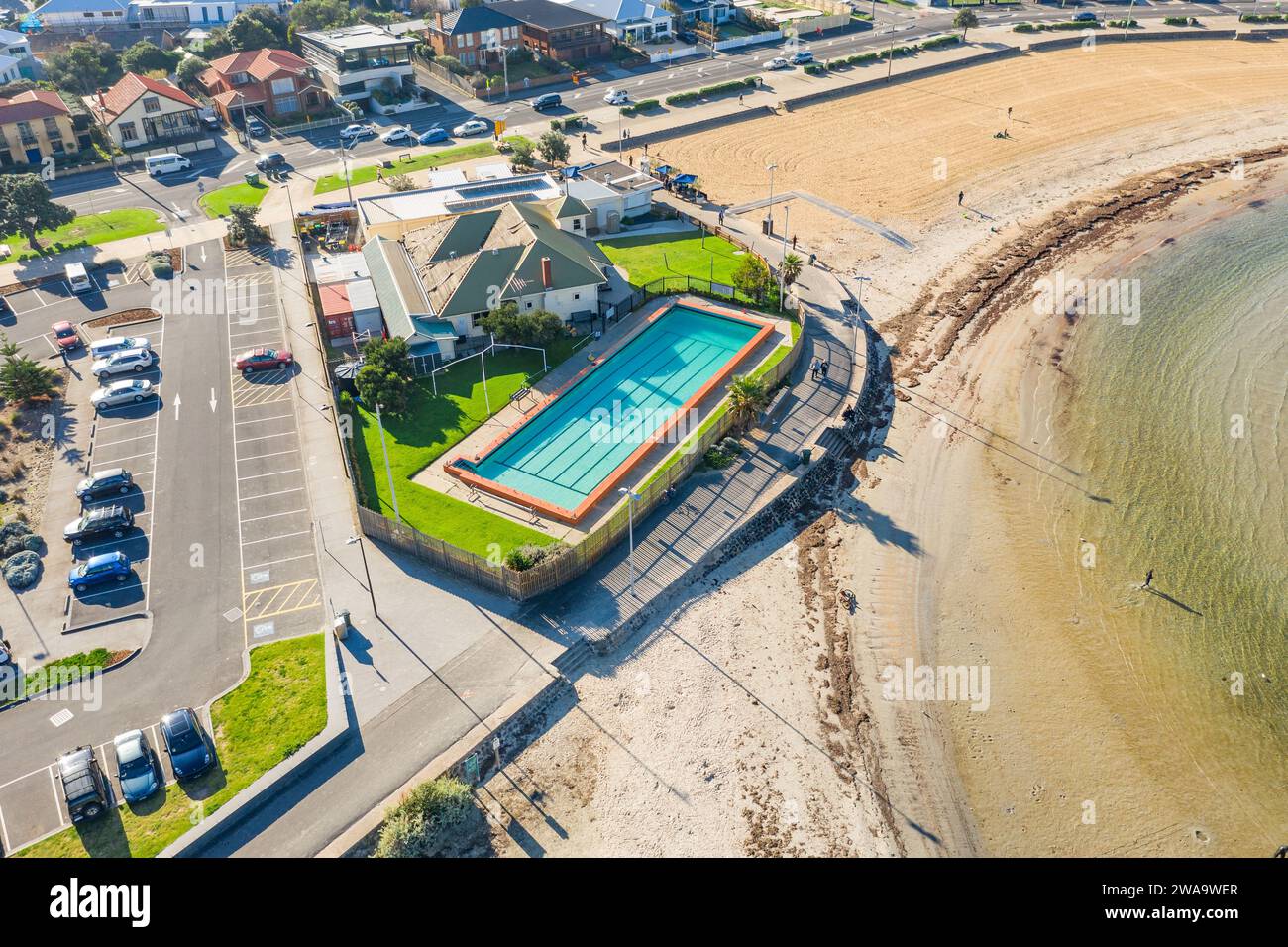 Aerial view of a coastal swimming pool between a carpark and a sandy ...