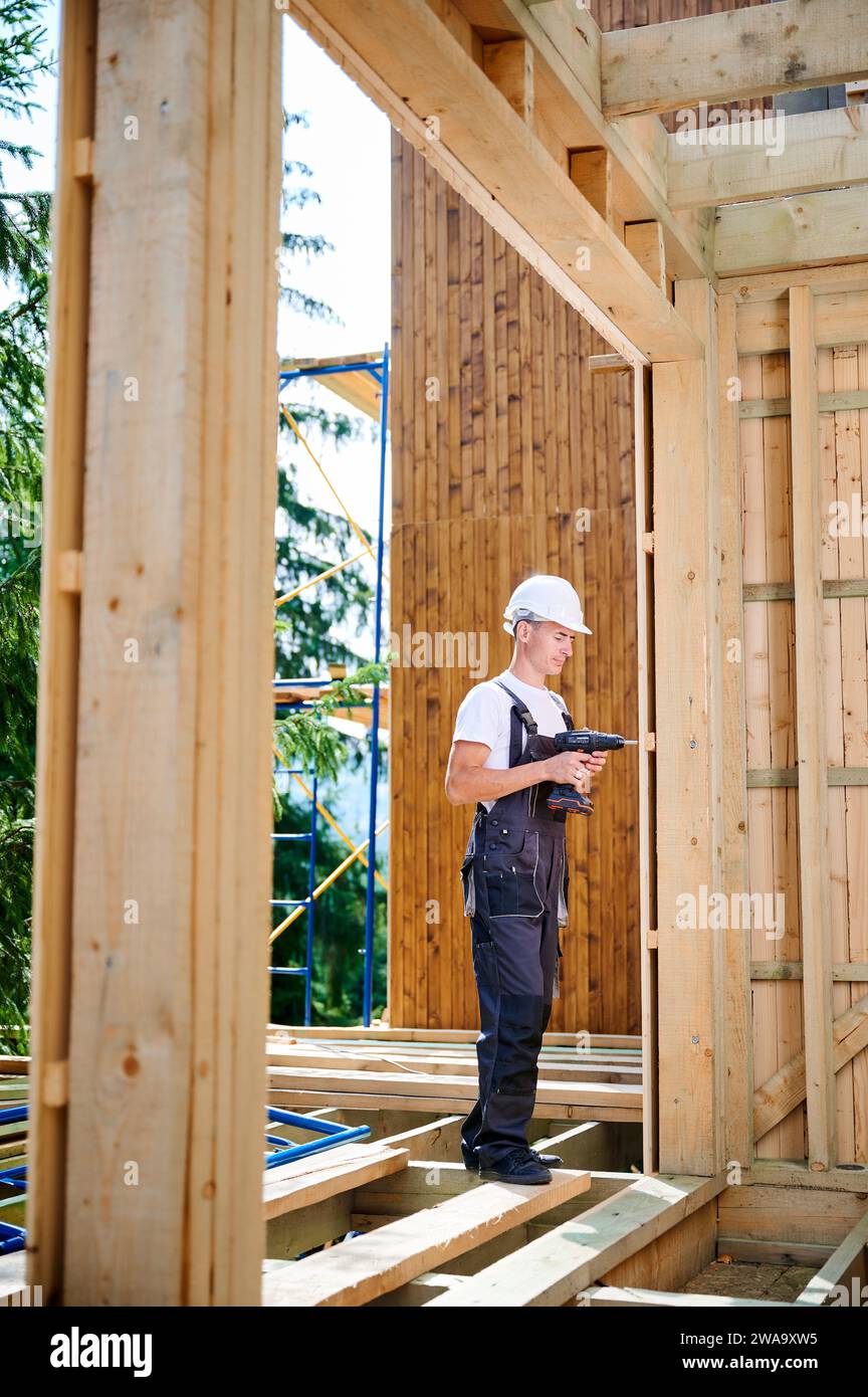 Carpenter constructing wooden framed house. Man worker cladding facade ...