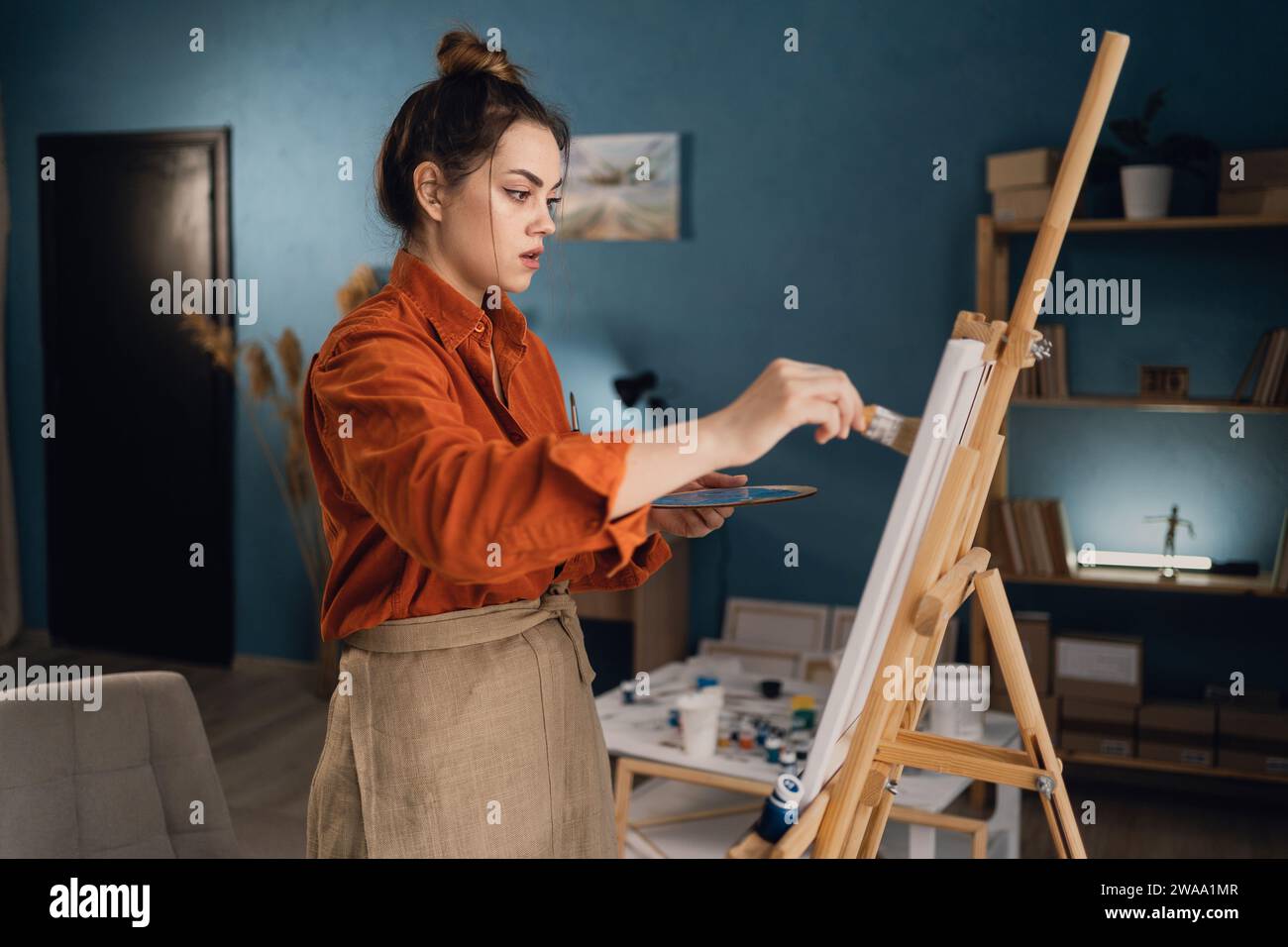 Creative latin female artist standing working on a new painting. Happy ...