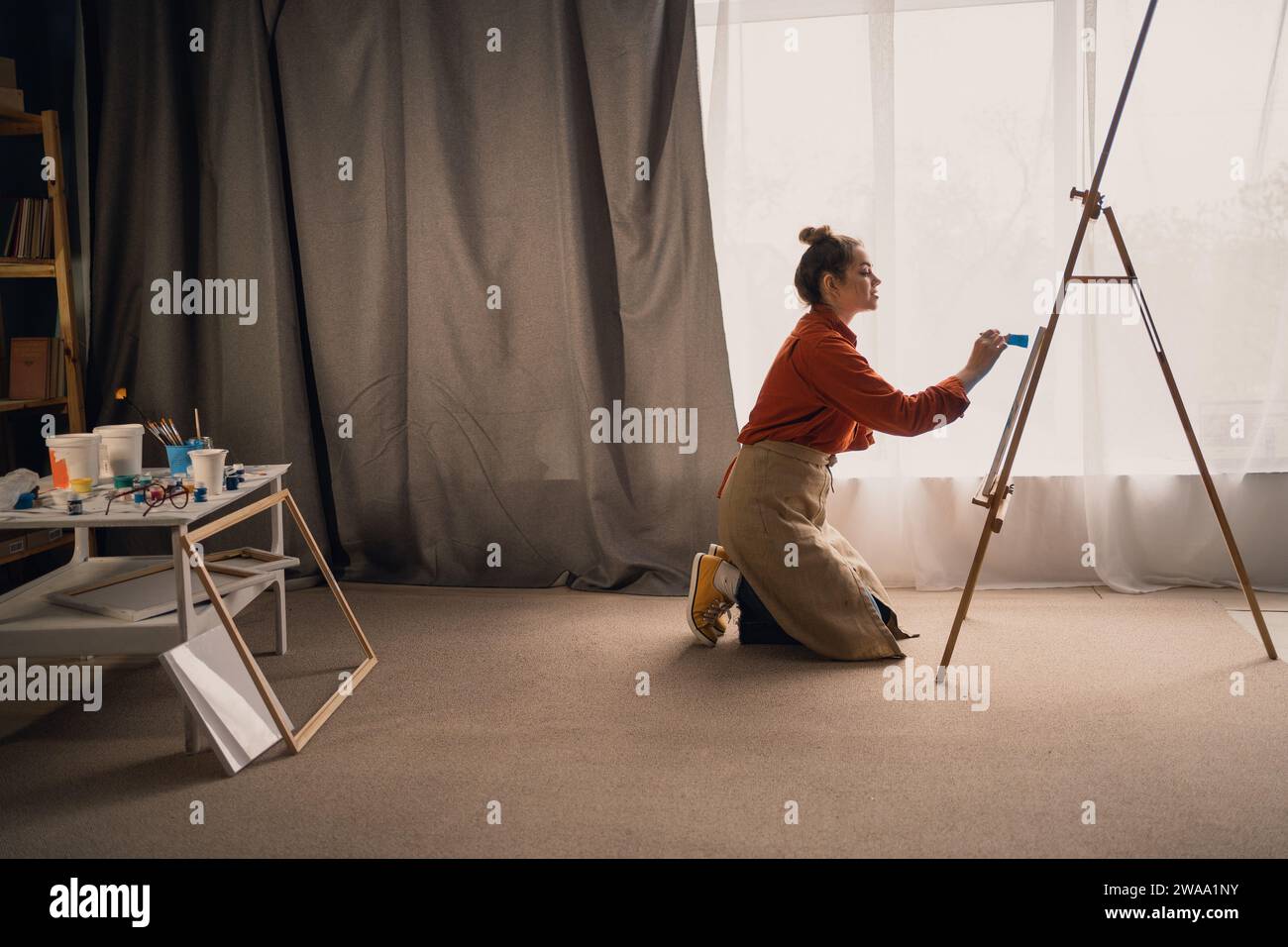 Beautiful female painter in art studio. Young talented artist working ...