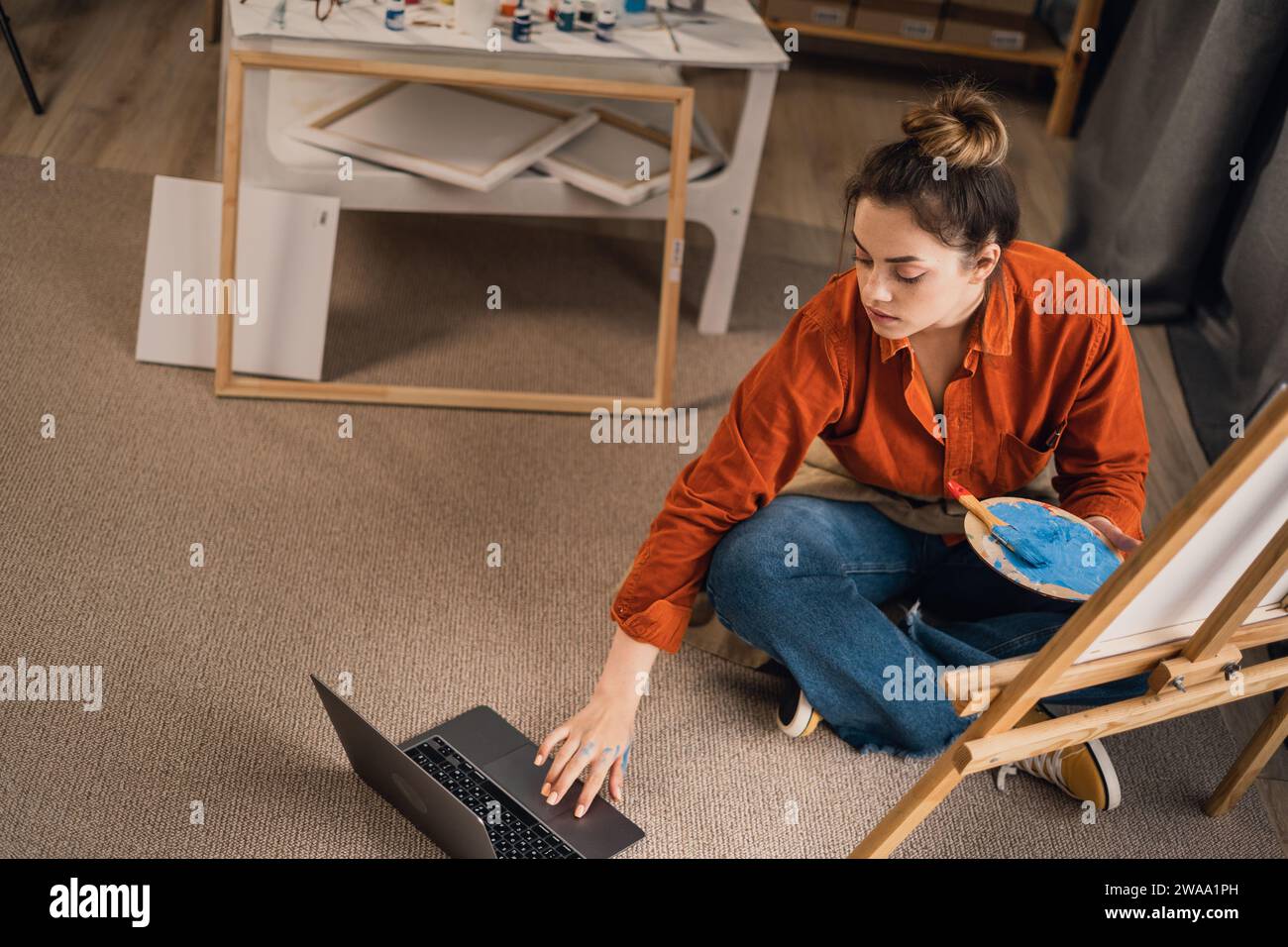 Artist sitting in her studio use laptop computer, video call with ...