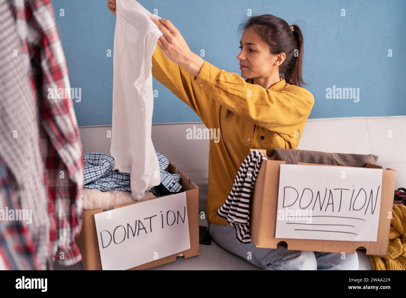 Donation, charity, volunteer concept. Woman putting Clothes into ...