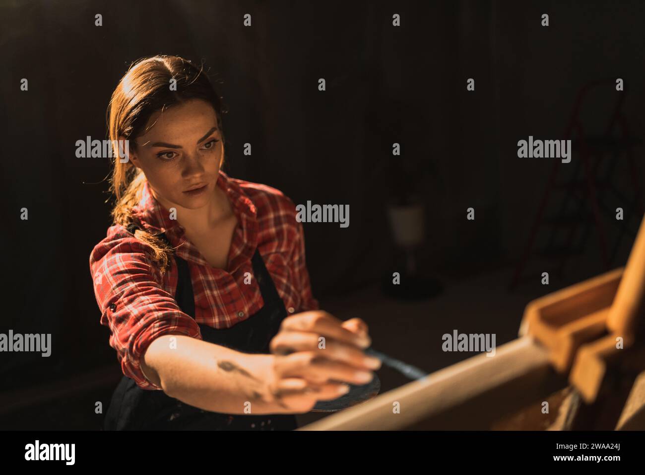 Female artist works on abstract oil painting in dark creative studio ...