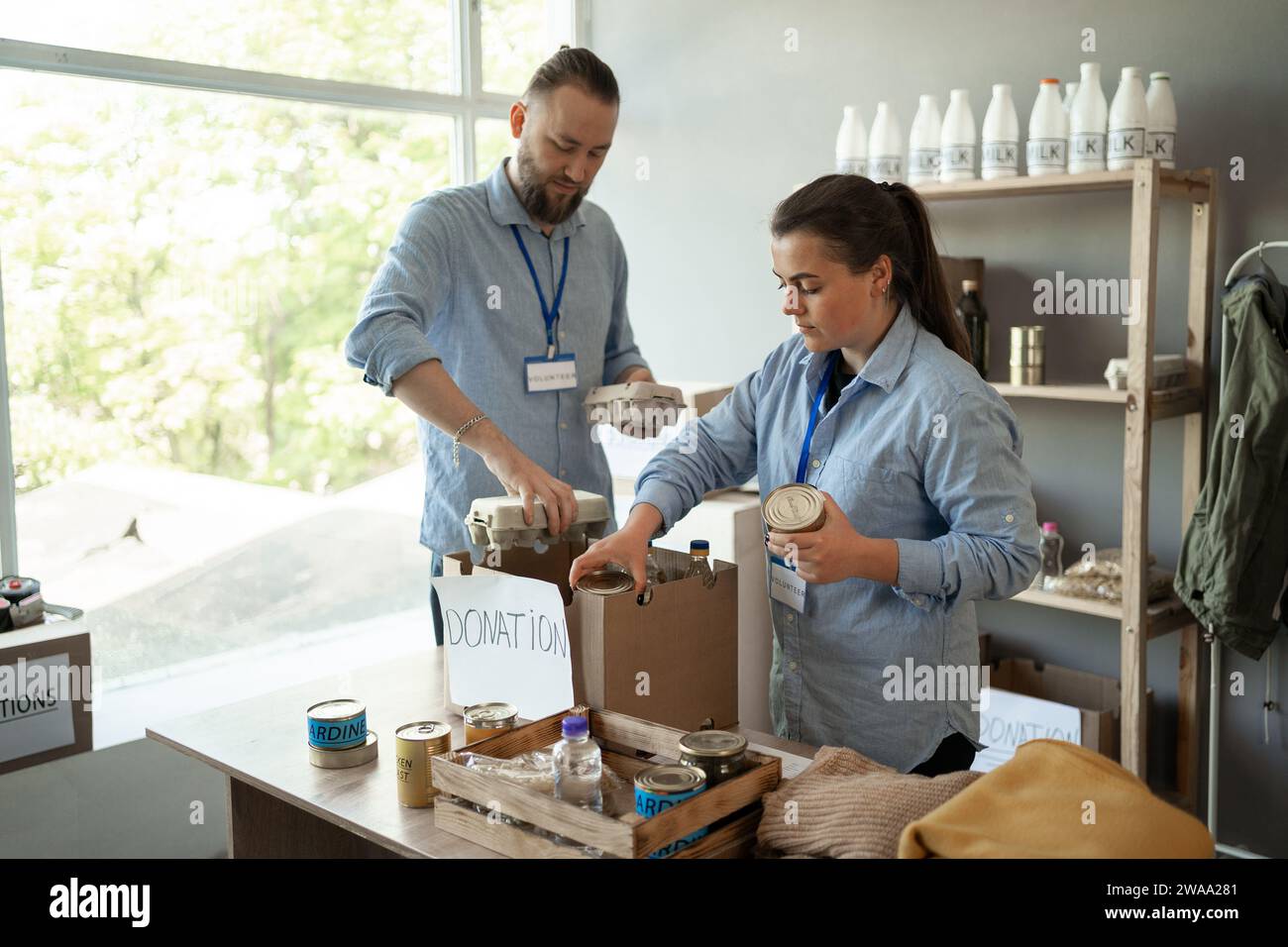 Group of volunteers packing food in boxes according to list on ...