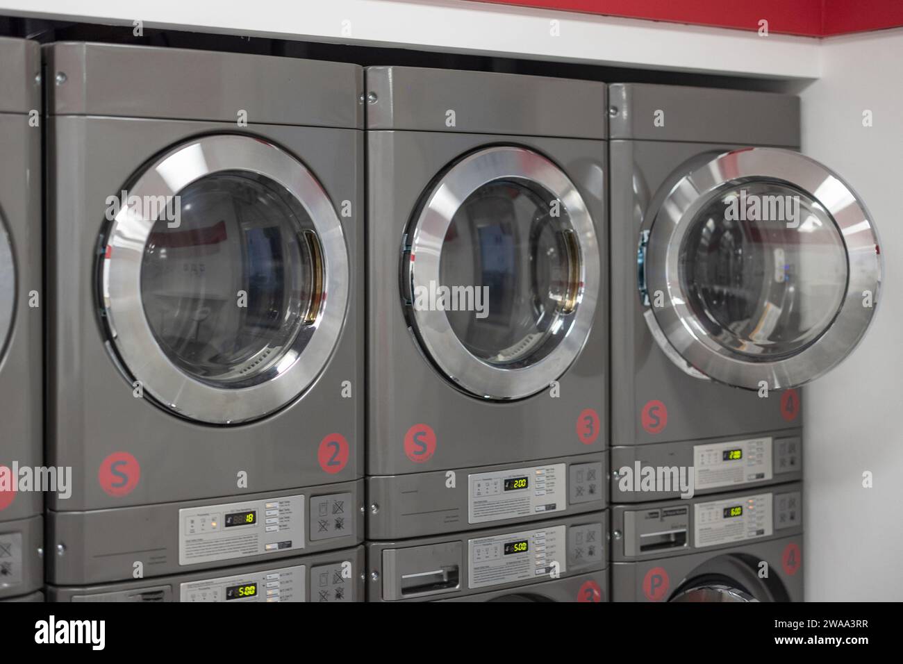 Multiple washing machines stacked one onto another in a laundromat ...