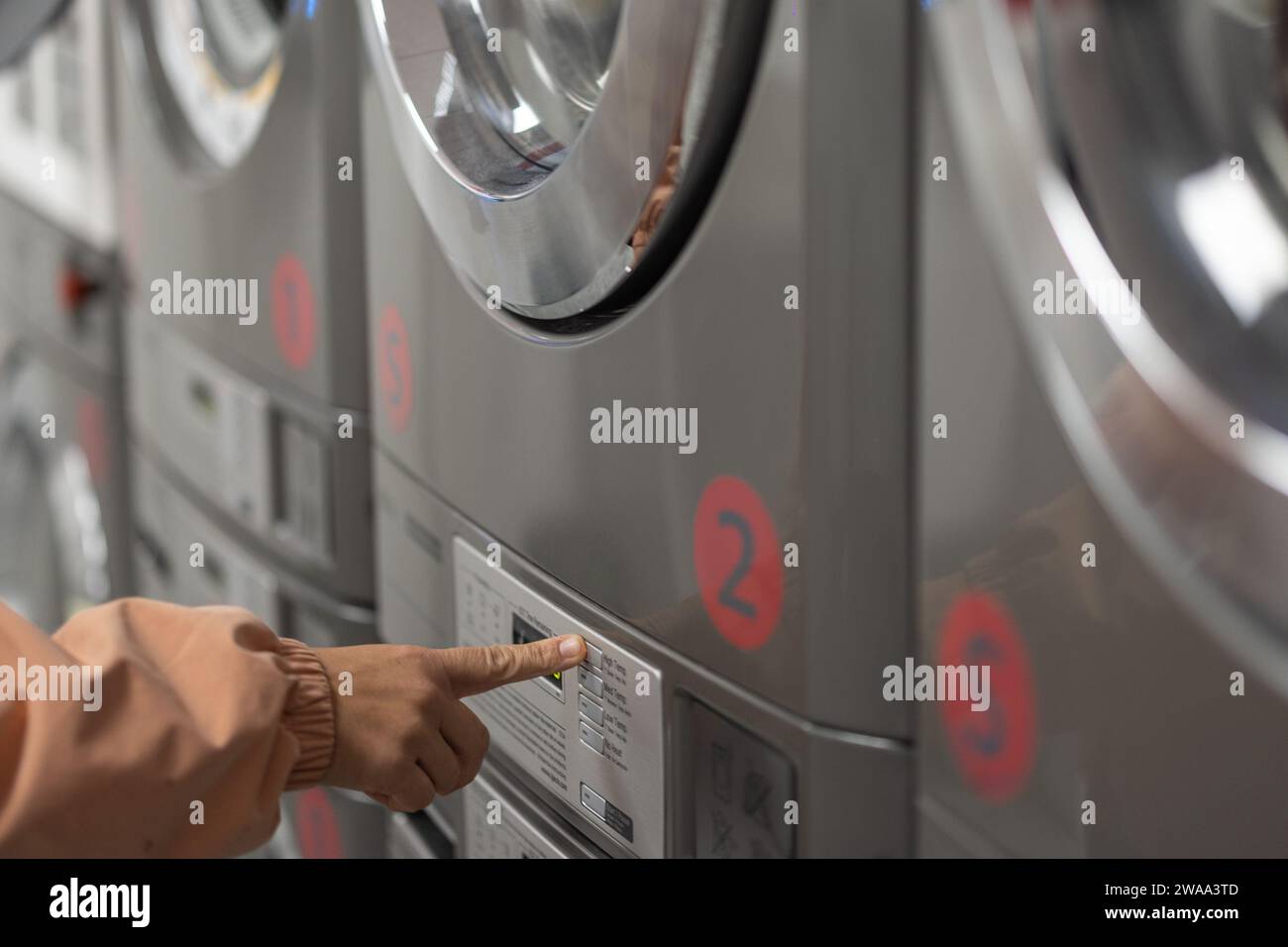 Female hand visible pushing a button on the machine at a laundromat ...