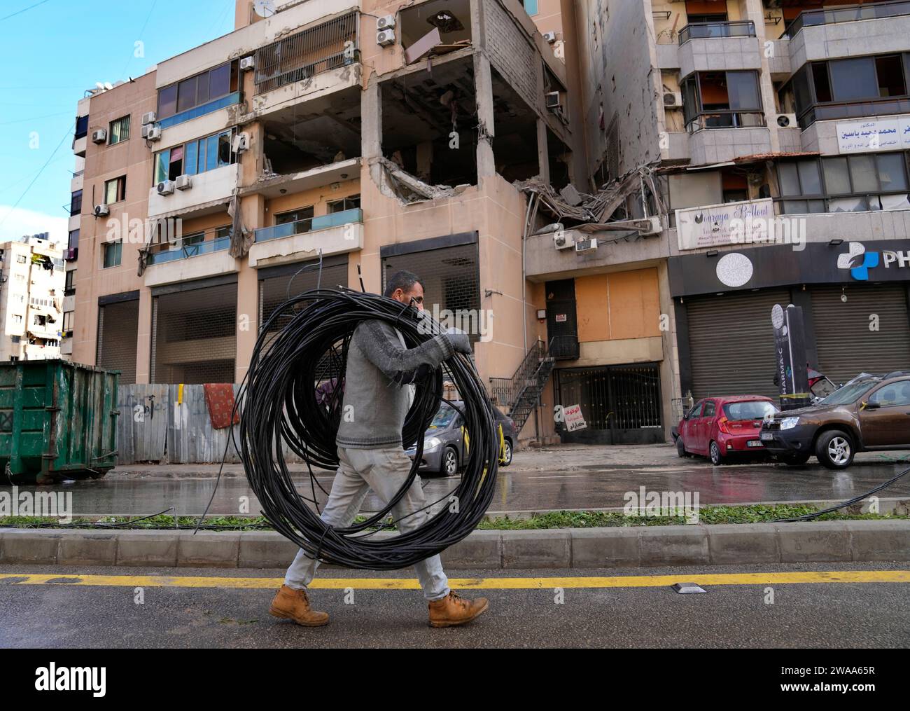 A worker carries power cables passes in front of an apartment building ...