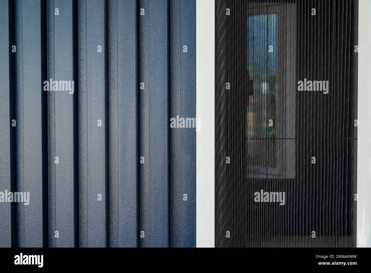 House with a facade covered with dark blue PVC panels and fly screen ...