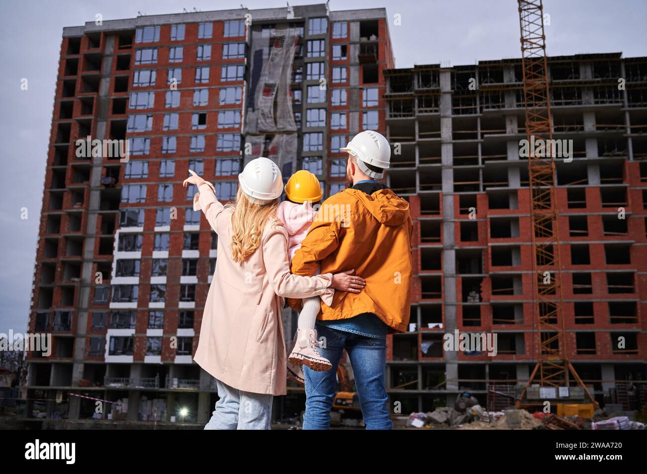 Back view of woman pointing at apartment building under constructing ...