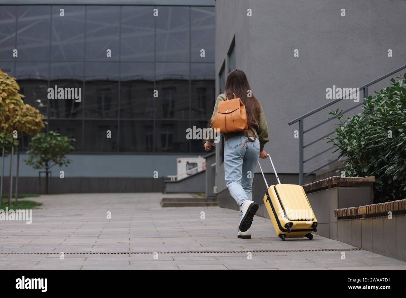 Being late. Woman with backpack and suitcase walking outdoors, back ...