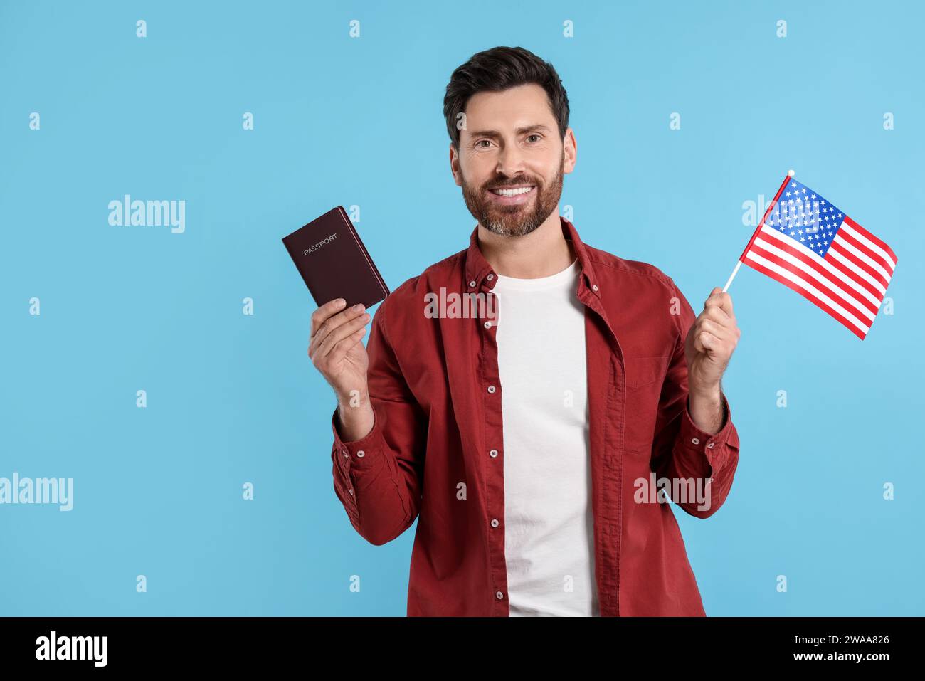 Immigration. Happy man with passport and American flag on light blue ...