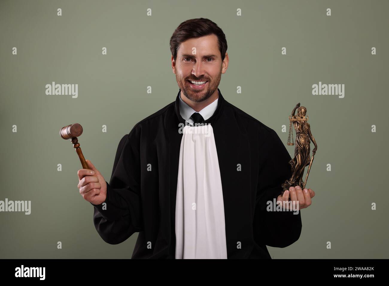 Happy judge with gavel and figure of Lady Justice on green background ...