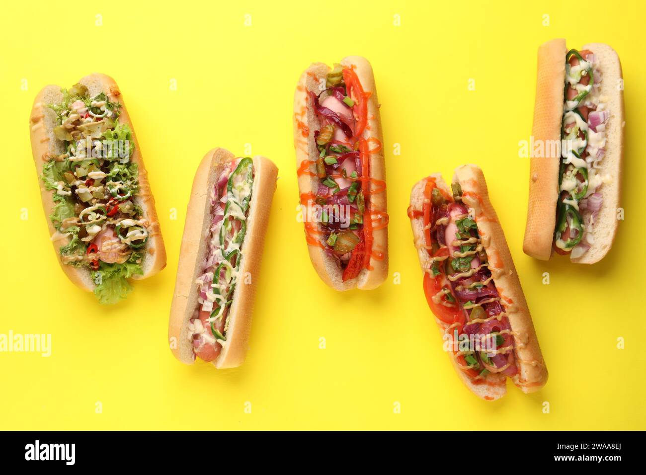 Delicious hot dogs with different toppings on yellow background, flat ...