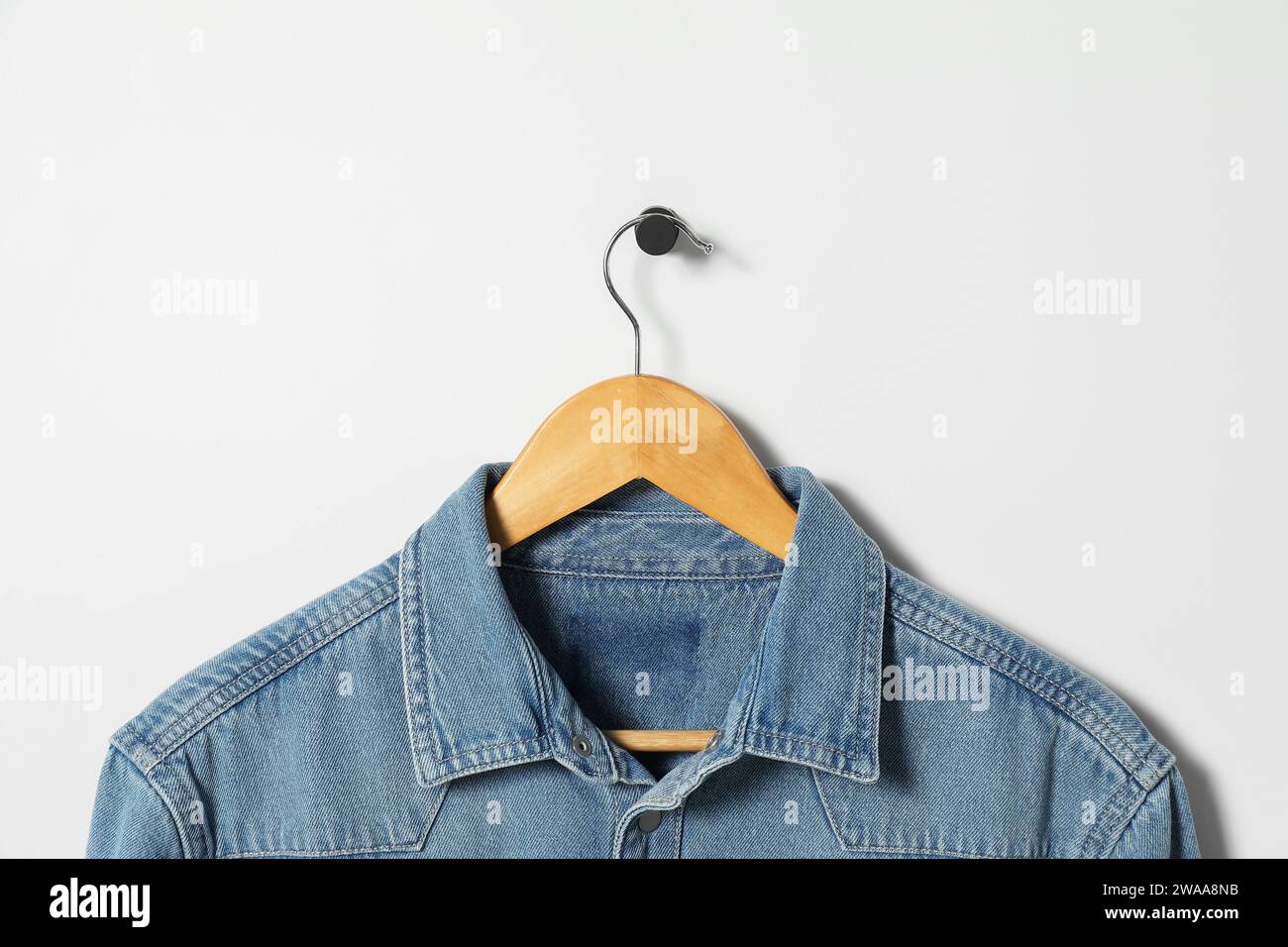 Hanger with denim shirt on white wall Stock Photo - Alamy