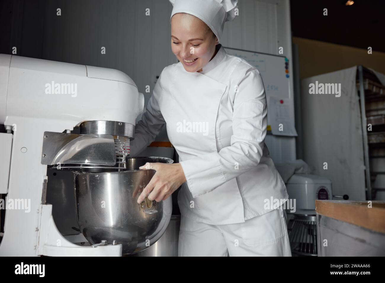 Happy woman chef baker using automated dough mixing machine Stock Photo ...