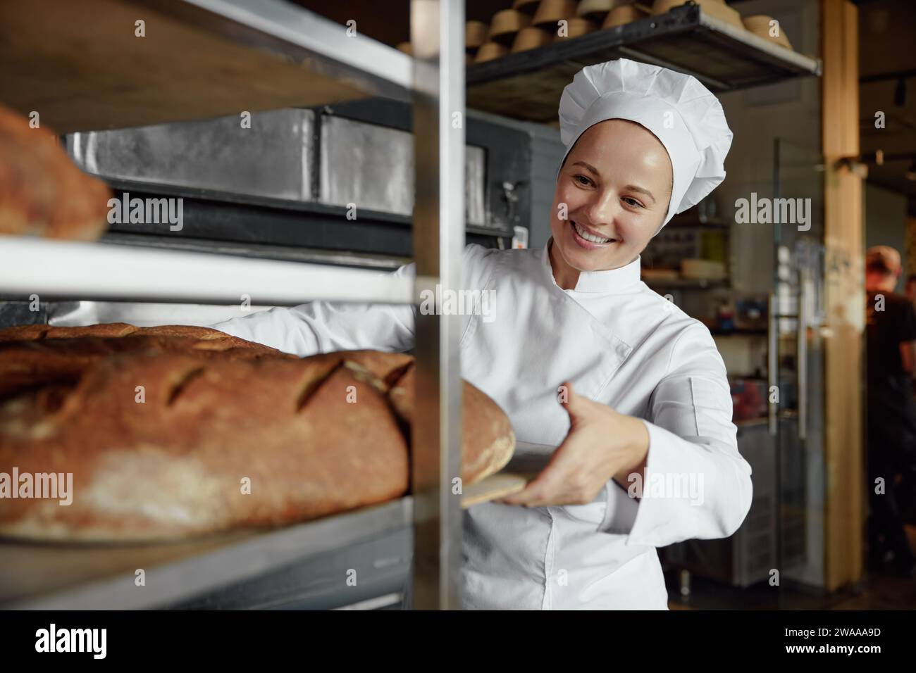 Baker smiling happily pushing rack with fresh baked bread Stock Photo ...
