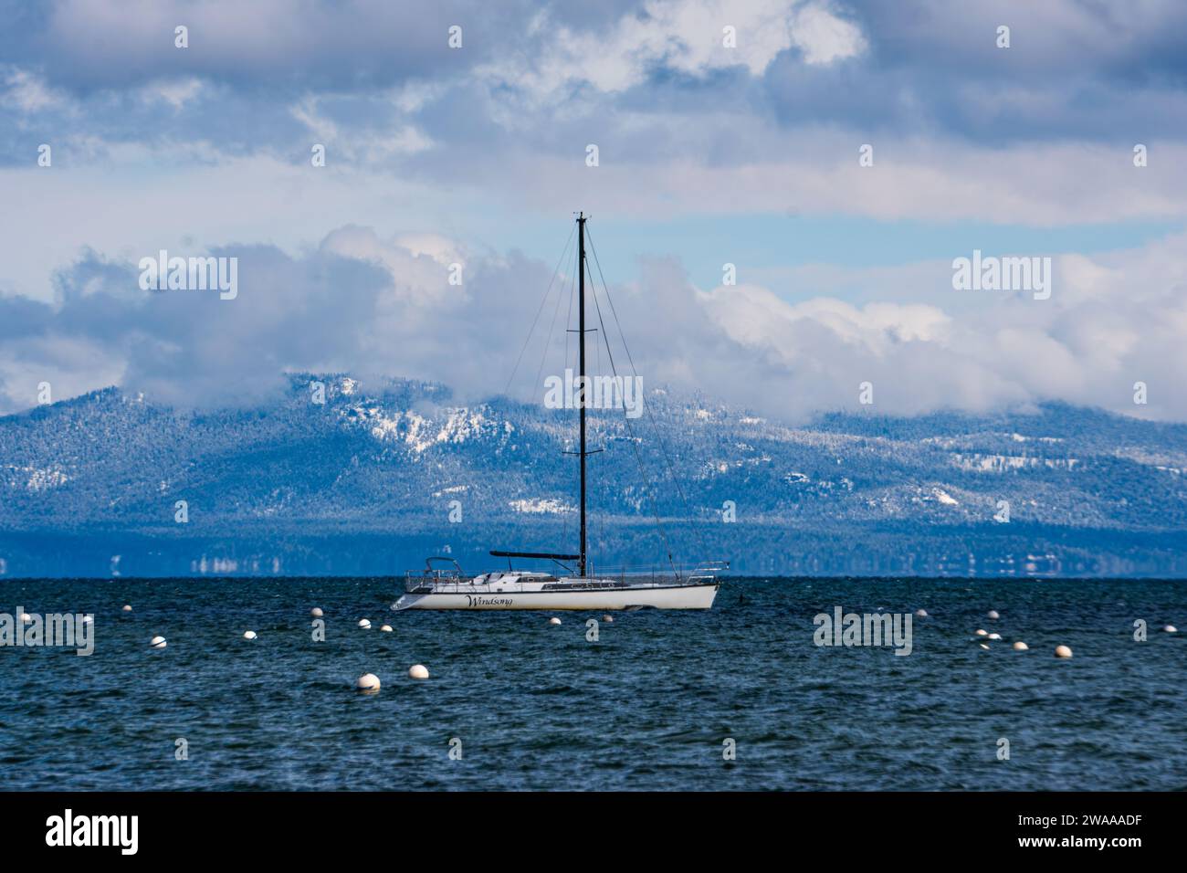 A sailboat anchored on lake Tahoe after a late spring snow storm, with ...