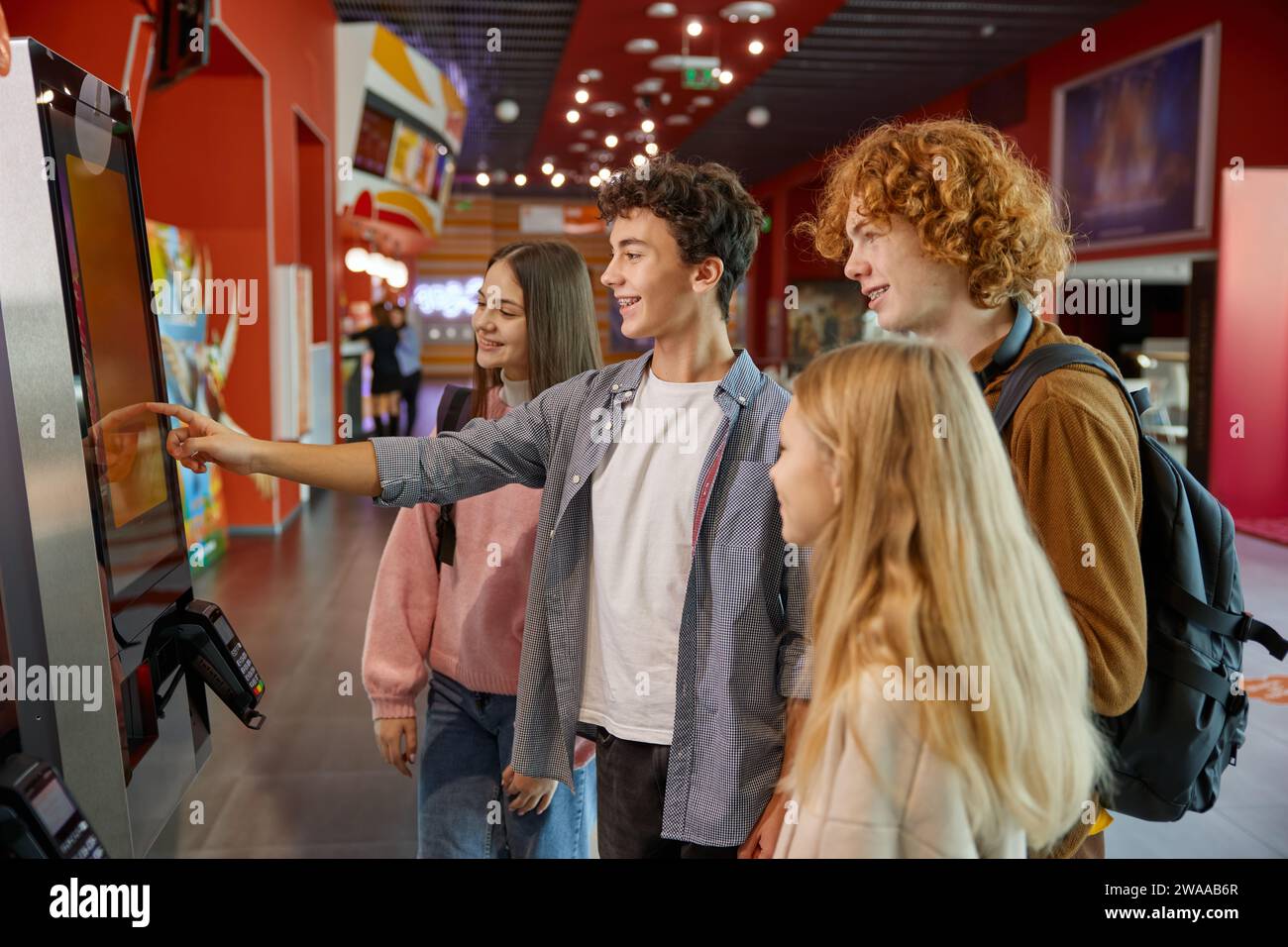 Teen friends using modern self-service kiosk at shopping mall Stock ...