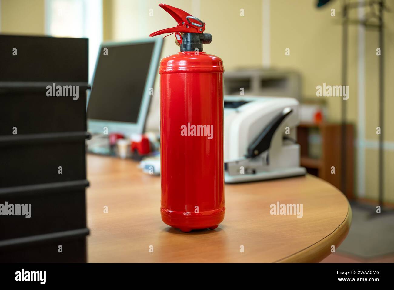 Fire extinguisher in workplace office against plain neutral background ...