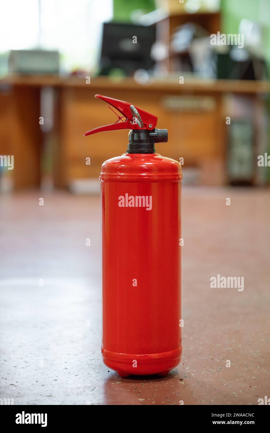 Fire extinguisher in workplace office against plain neutral background ...