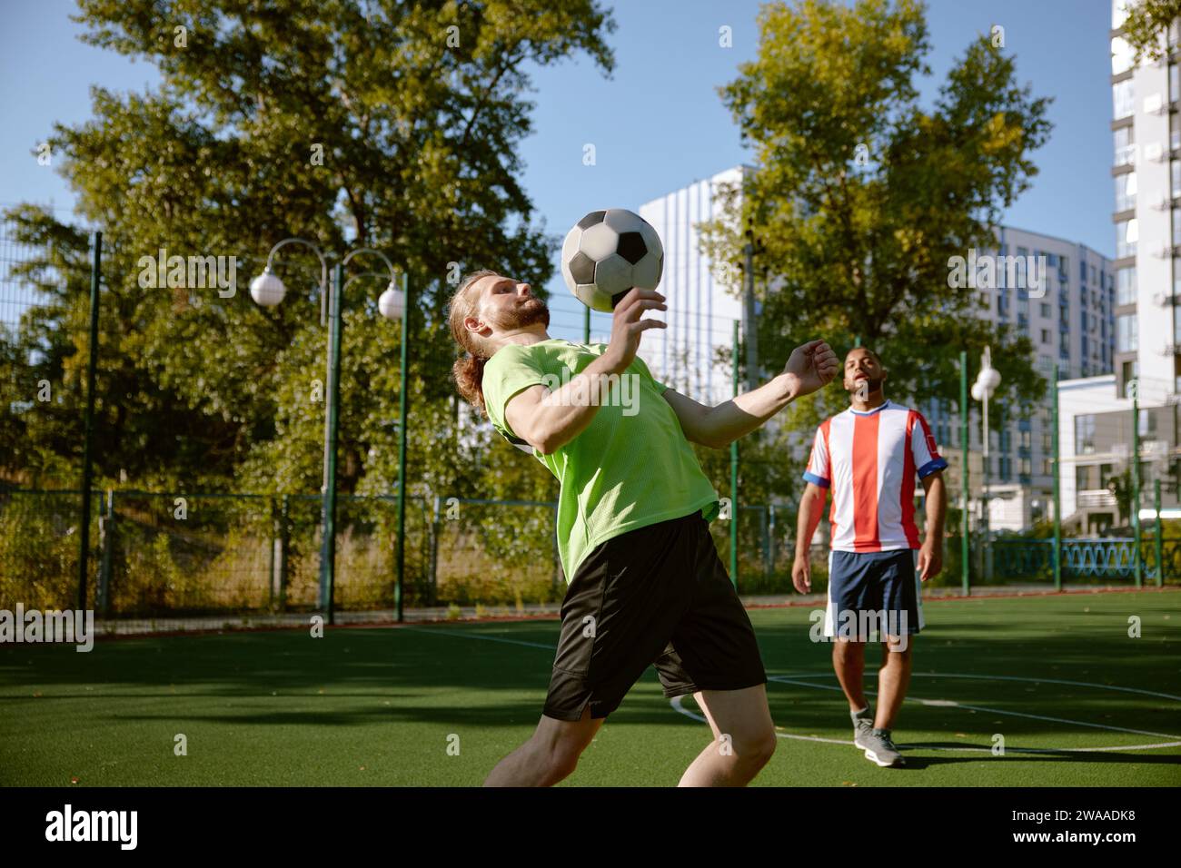 Male football player hitting ball with his chest training at street ...