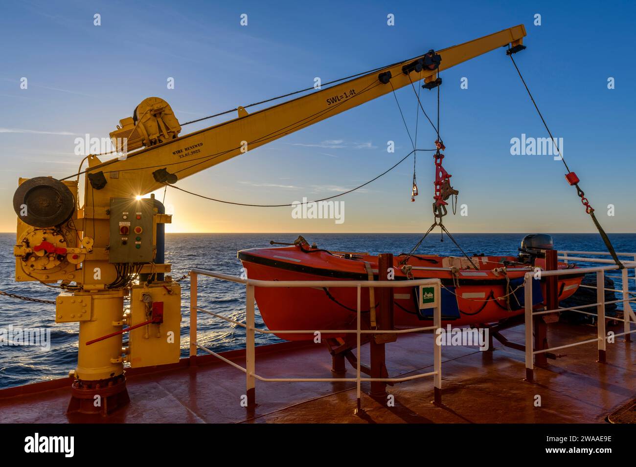 Orange rescue boat on big cargo vessel and crane. Man over board drill ...