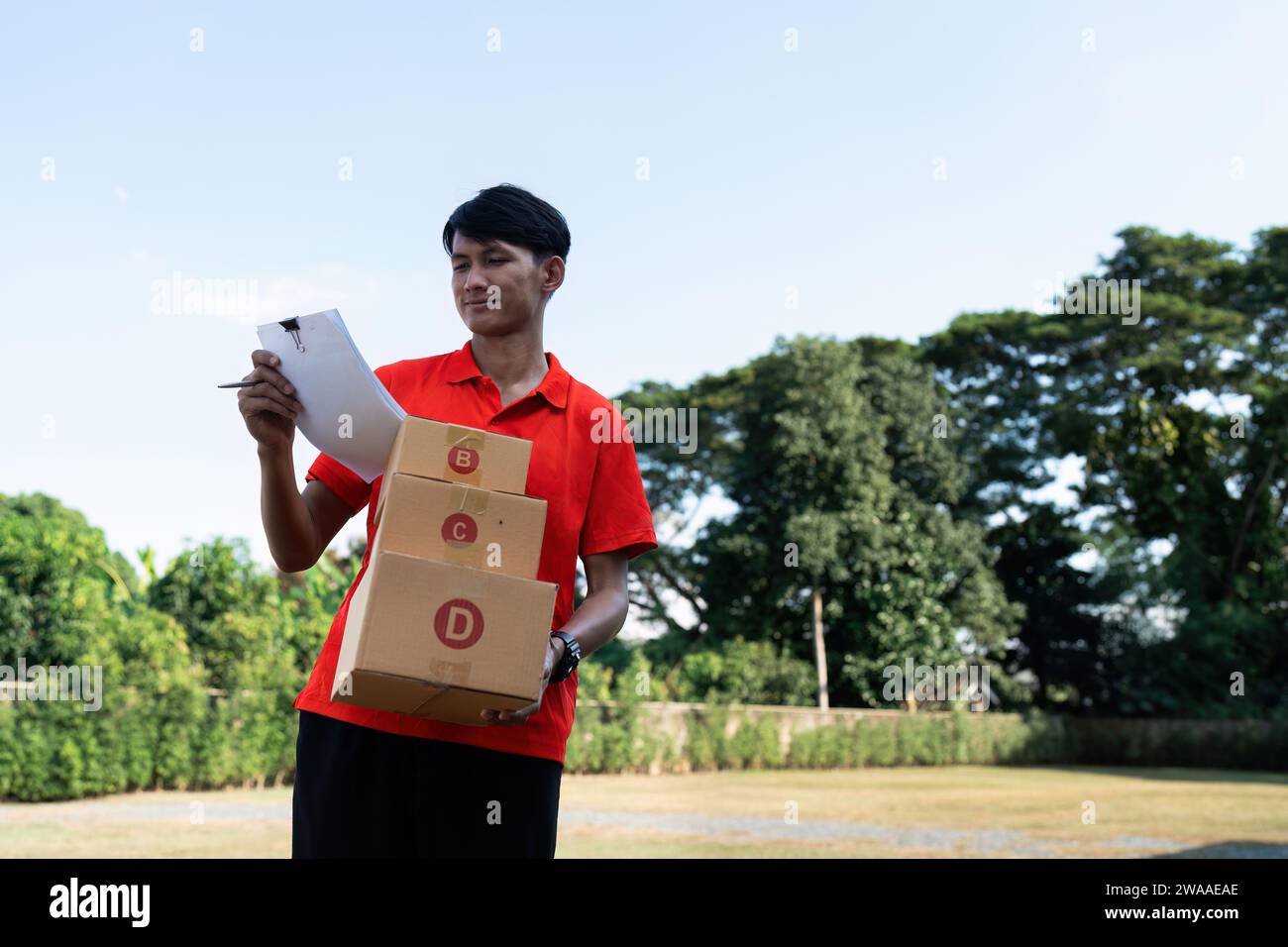 Young delivery man checking detail about parcel. Male postman courier ...