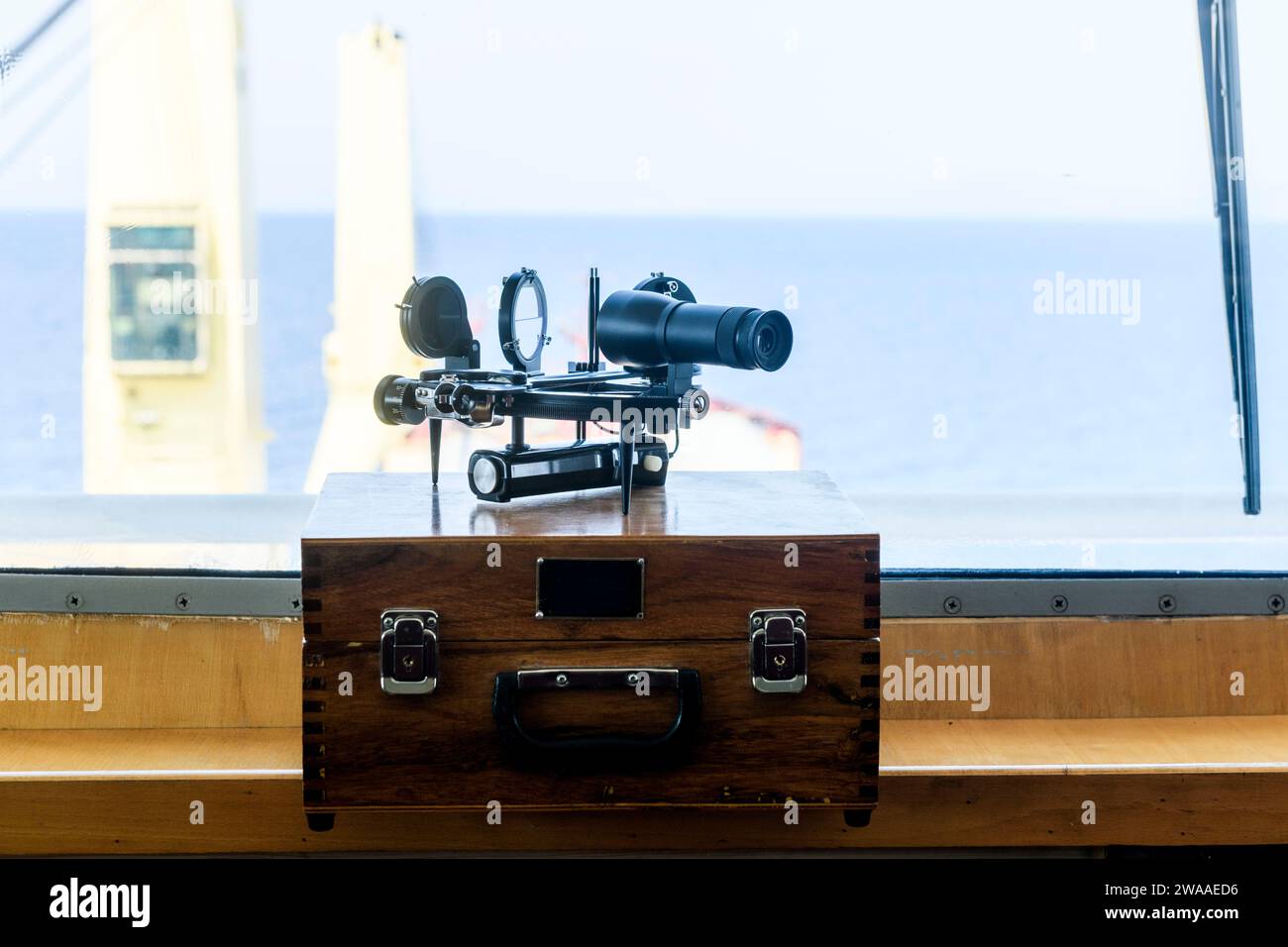 Nautical black sextant placed on wooden box in navigational bridge ...