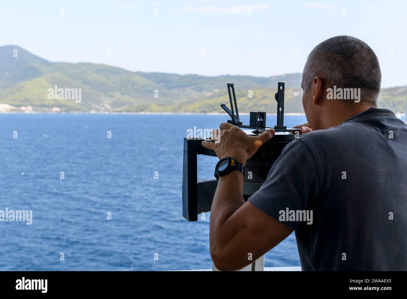 Navigational officer taking bearing with azimuth ring on gyro compass ...
