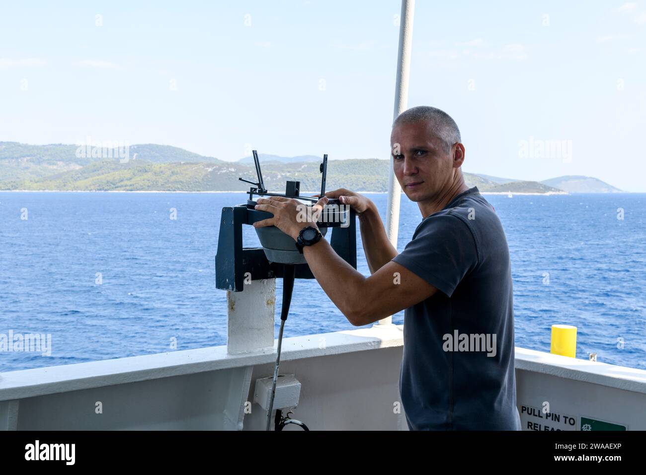 Navigational officer taking bearing with azimuth ring on gyro compass ...
